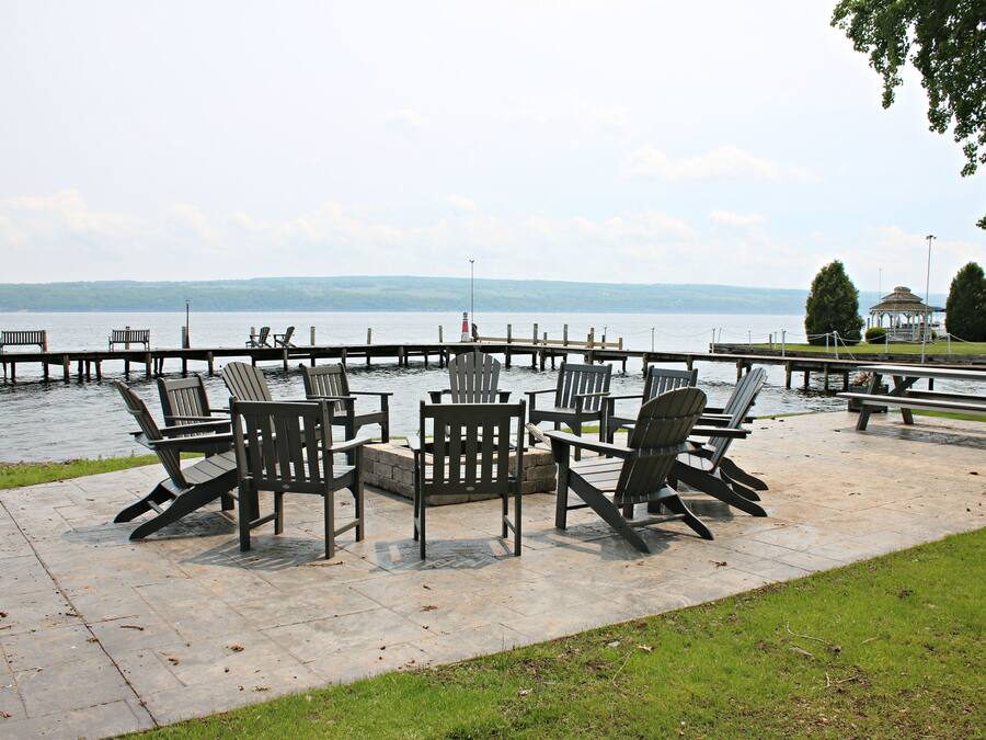 Um alpendre à beira do lago com cadeiras Adirondack e um coreto.