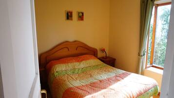 Quarto com cama de madeira, mesa de cabeceira e janela com cortinas.