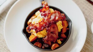 Prato de pequeno-almoço com ovos mexidos, bacon e batatas.