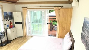 Um quarto com cama, guarda-roupa, ventoinha e vista para o exterior.