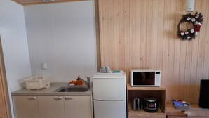 Uma cozinha compacta com pia, geladeira branca, micro-ondas e armário de madeira.