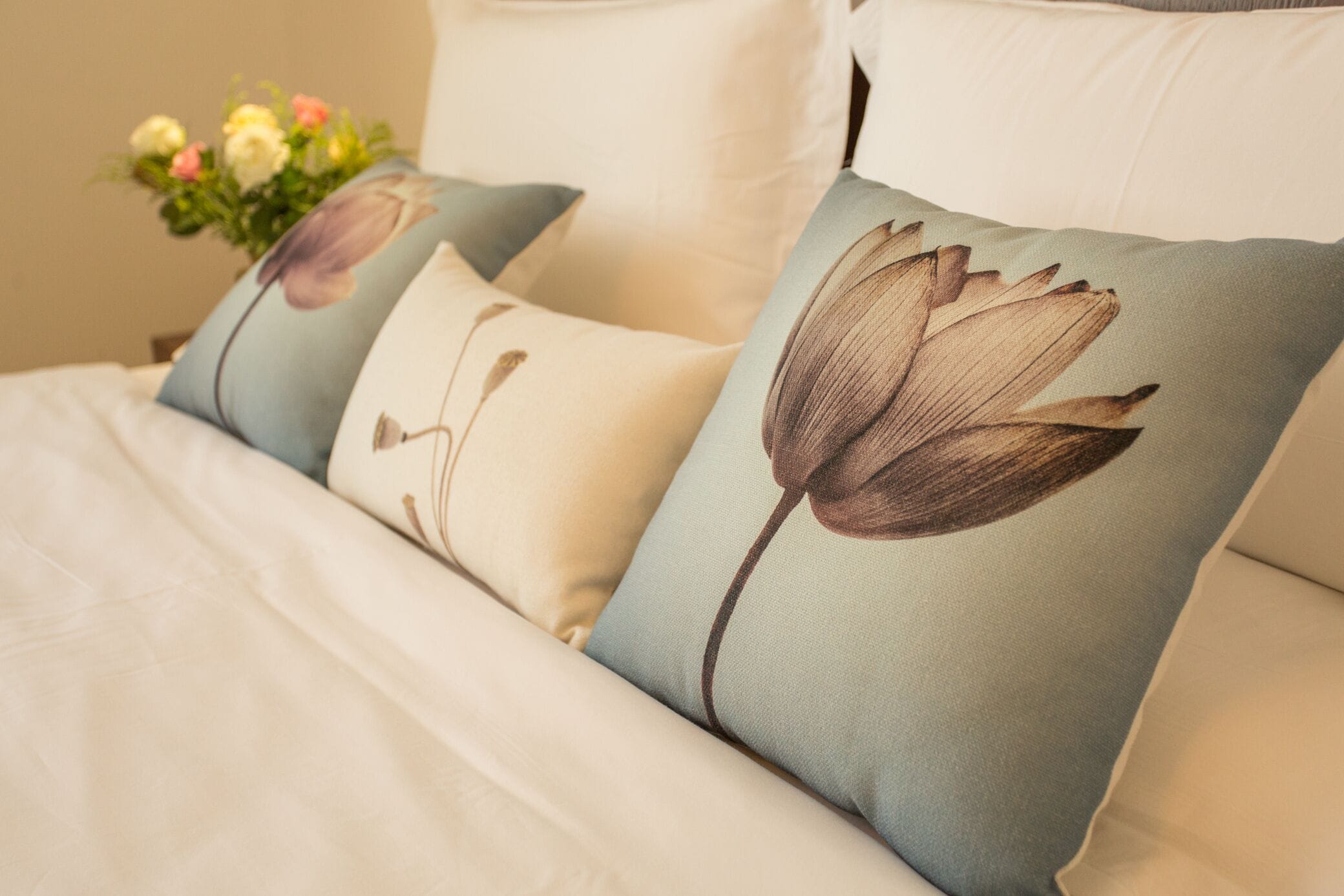 Cama com três almofadas estampadas com motivos florais.