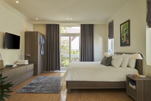 Quarto com uma cama grande, televisão, guarda-roupa, mesa de cabeceira com abajur e vista para o exterior.