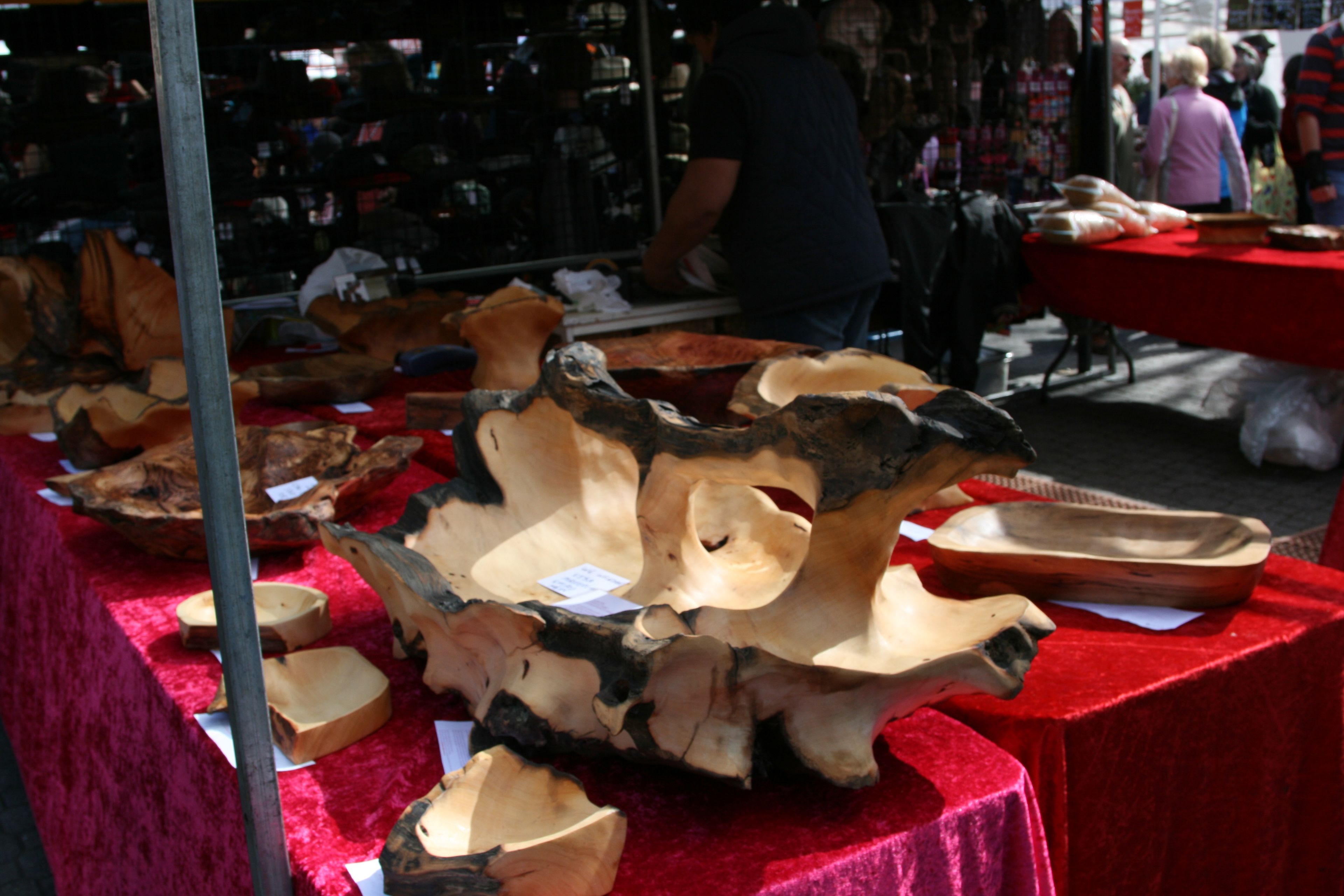 Uma mesa com várias tigelas e pratos de madeira expostos sobre um pano de mesa vermelho.