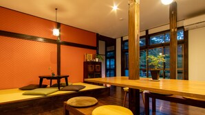 Quarto com um banco de madeira, uma mesa e vista para o exterior por grandes janelas.