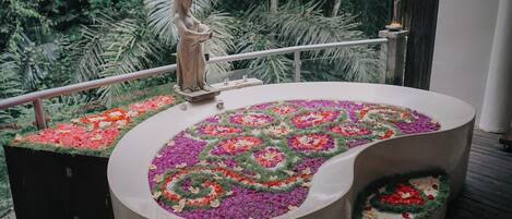 Uma banheira com um padrão floral, uma estátua e um corrimão.