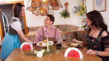 Uma mesa de jantar com uma vela, copos de vinho e um ventilador.