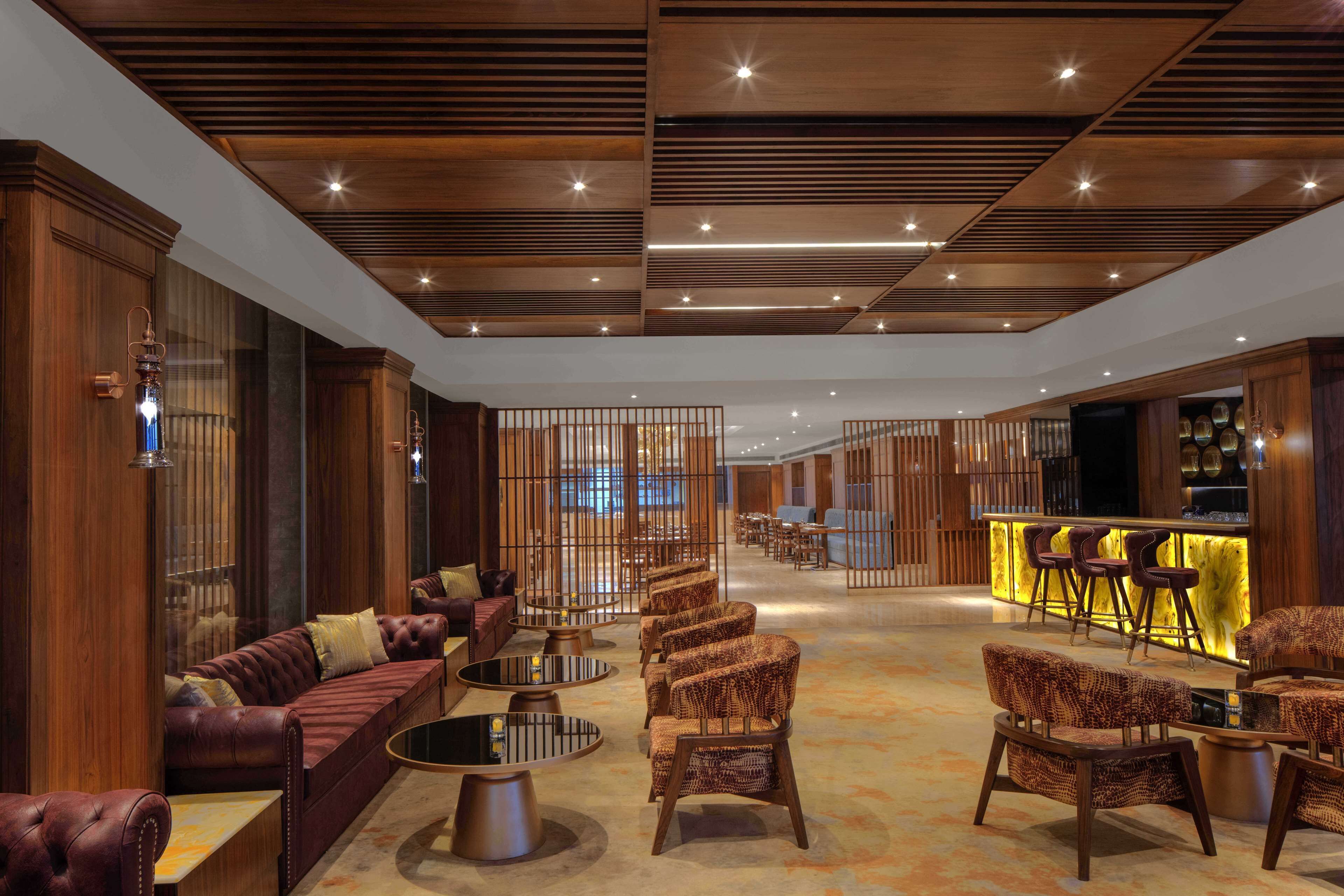 Uma ampla sala de estar com sofás de couro, cadeiras de vime e um bar com banquetas.