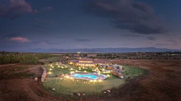Uma propriedade extensa com vários edifícios, piscina e gramado bem cuidado.