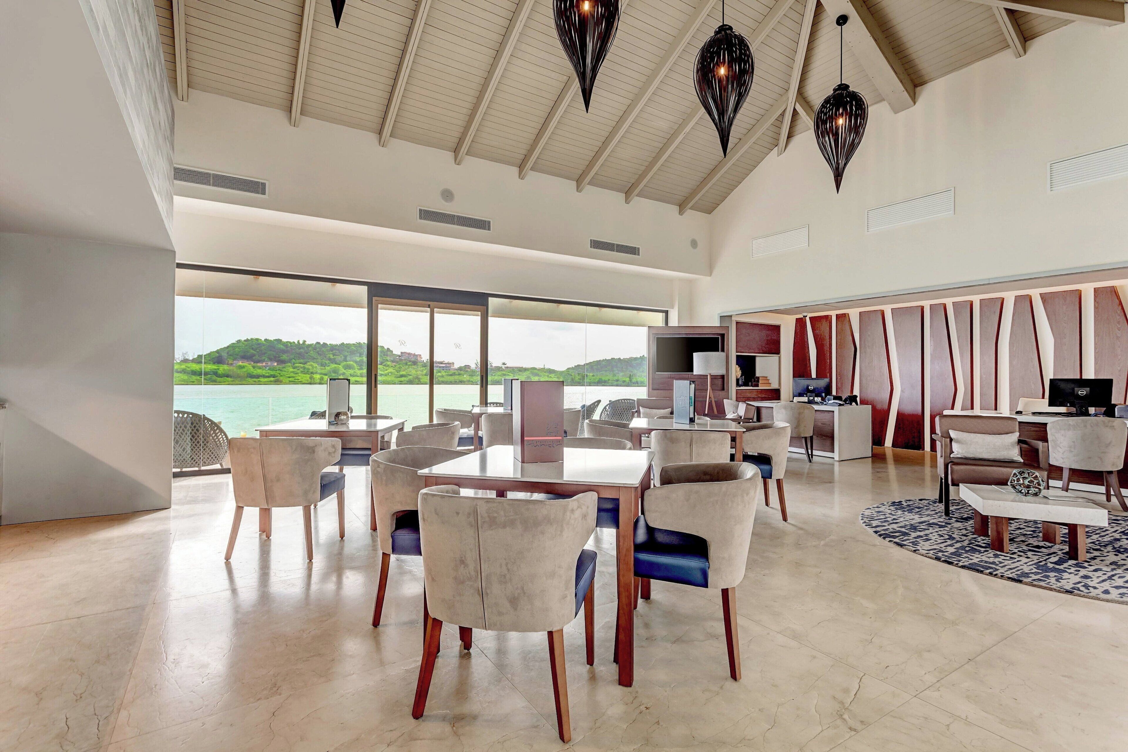 Uma sala de jantar ampla com uma mesa grande e cadeiras, vista para o mar e design de interiores moderno.