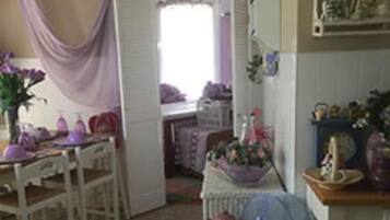 Quarto com uma mesa de jantar, cadeiras, uma janela com cortinas e um painel decorativo.
