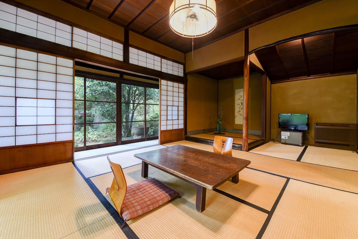 Um quarto japonês tradicional com piso de tatame, uma mesa baixa e portas deslizantes.
