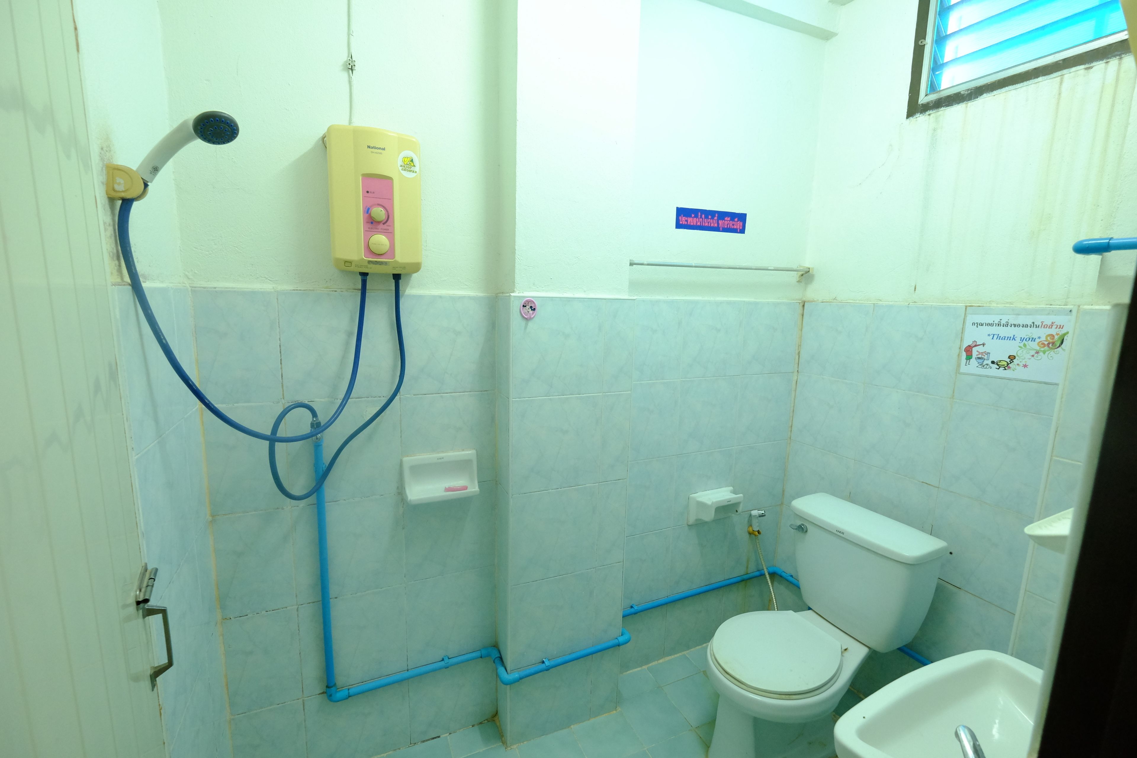 Casa de banho com sanita, lavatório e chuveiro.