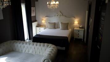 Quarto com cama grande, duas mesas de cabeceira, um candelabro e um chaise-longue.