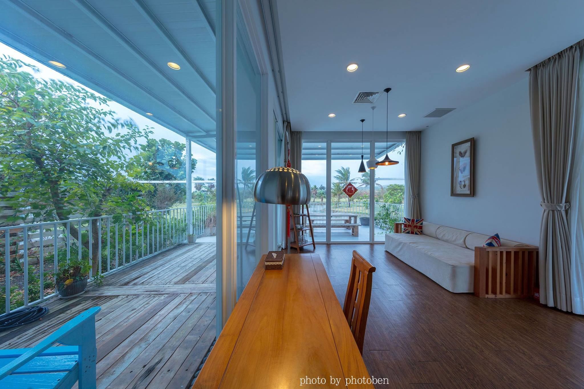 Sala moderna com mesa de jantar de madeira, sofá e uma janela grande com vista para áreas verdes.