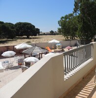 Um terraço com área de estar ao ar livre, guarda-sóis e um espaço de recreação infantil.