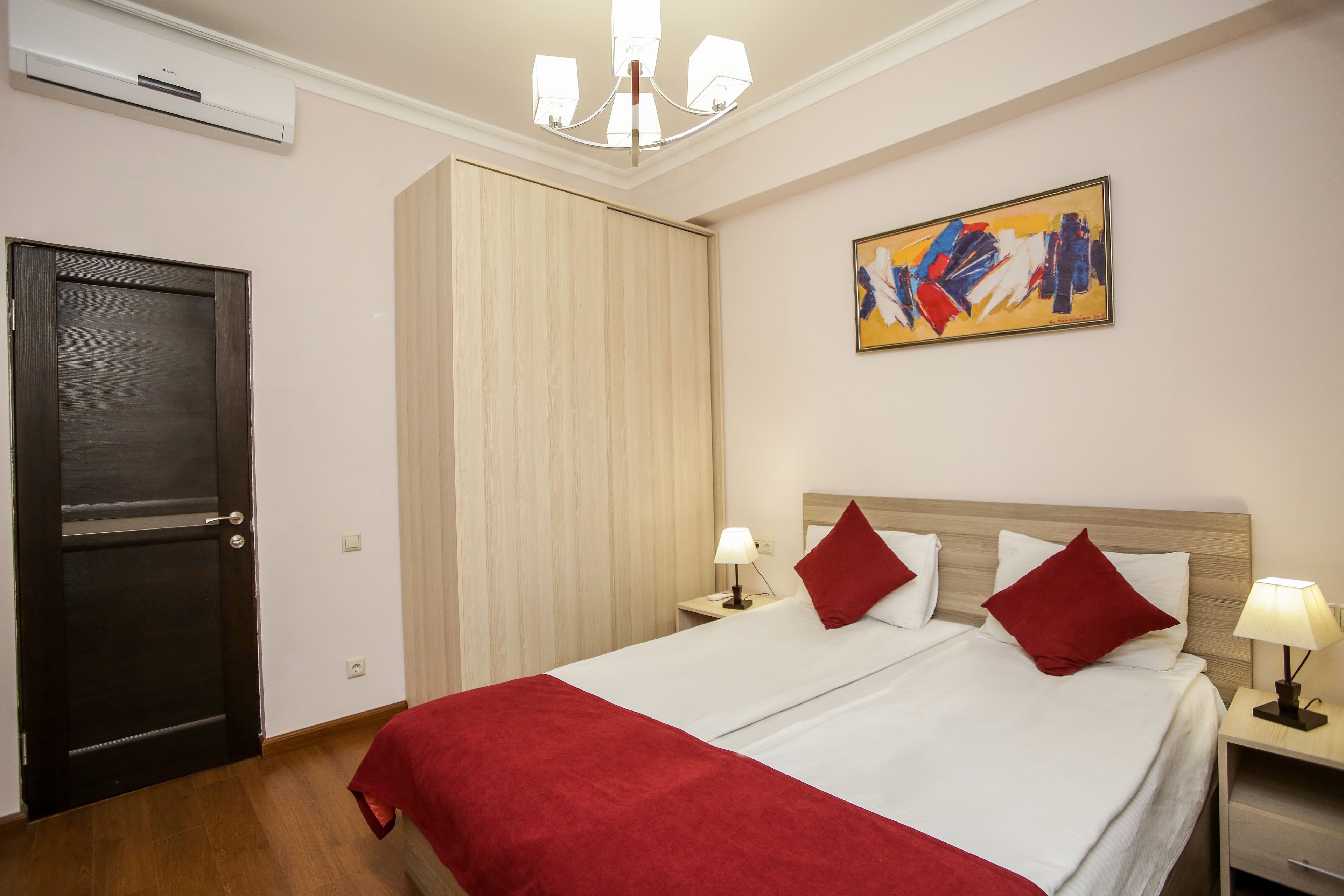 Quarto de hotel com cama, abajures, um quadro e um guarda-roupa.