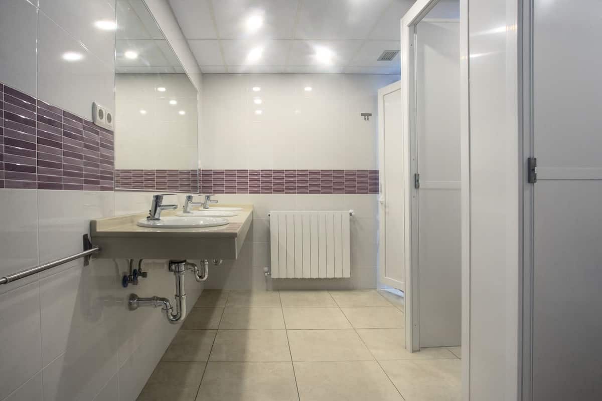 Um banheiro moderno com duas pias, um espelho e um porta-toalhas.