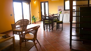Uma sala de jantar com cadeiras de vime, uma mesa e um vaso de planta.