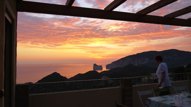 Vista do pôr do sol a partir de uma varanda com mesa posta para refeição.