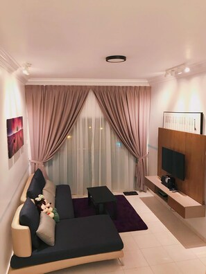 Uma sala de estar moderna com um sofá, uma mesa de centro, uma televisão de tela plana e uma TV montada na parede.