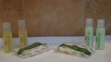 Casa de banho com lavatório branco, quatro frascos de produtos BioNatur® e dois saquinhos de chá BioNatur®.