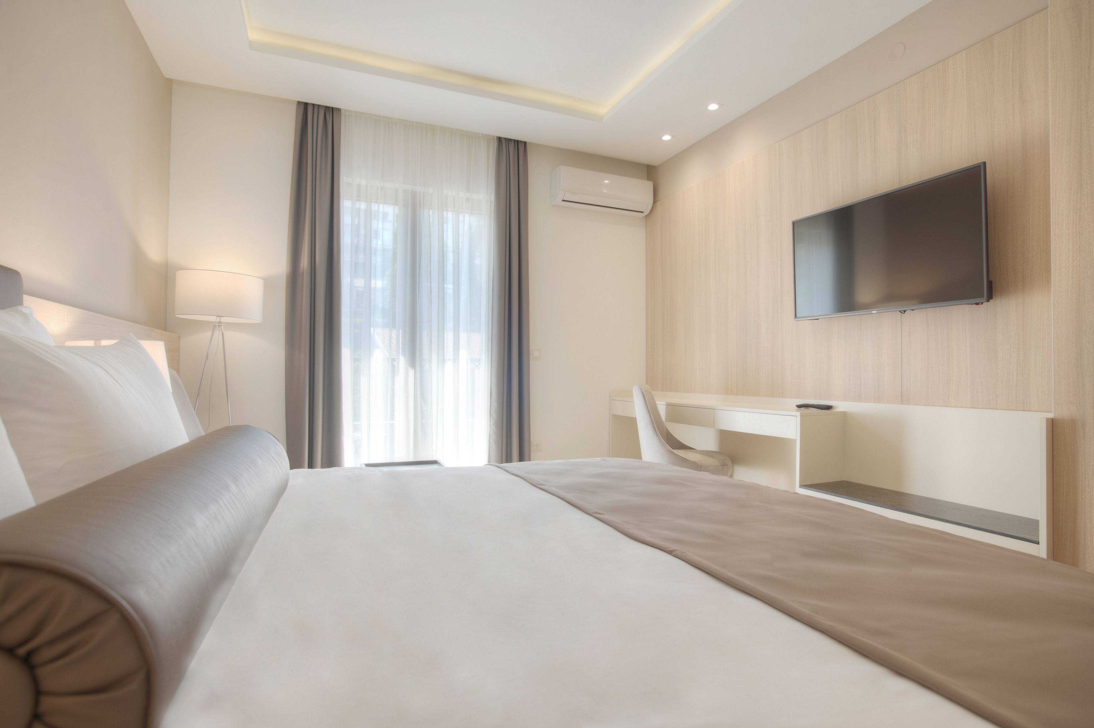 Quarto de hotel moderno com uma cama grande, uma escrivaninha, uma TV de tela plana e ar condicionado.