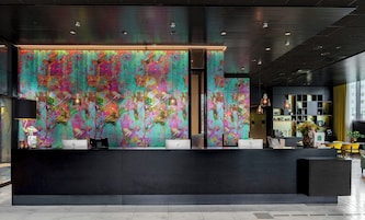 Uma área de recepção com um mural abstrato e colorido, um balcão de recepção preto e um design de interiores moderno.