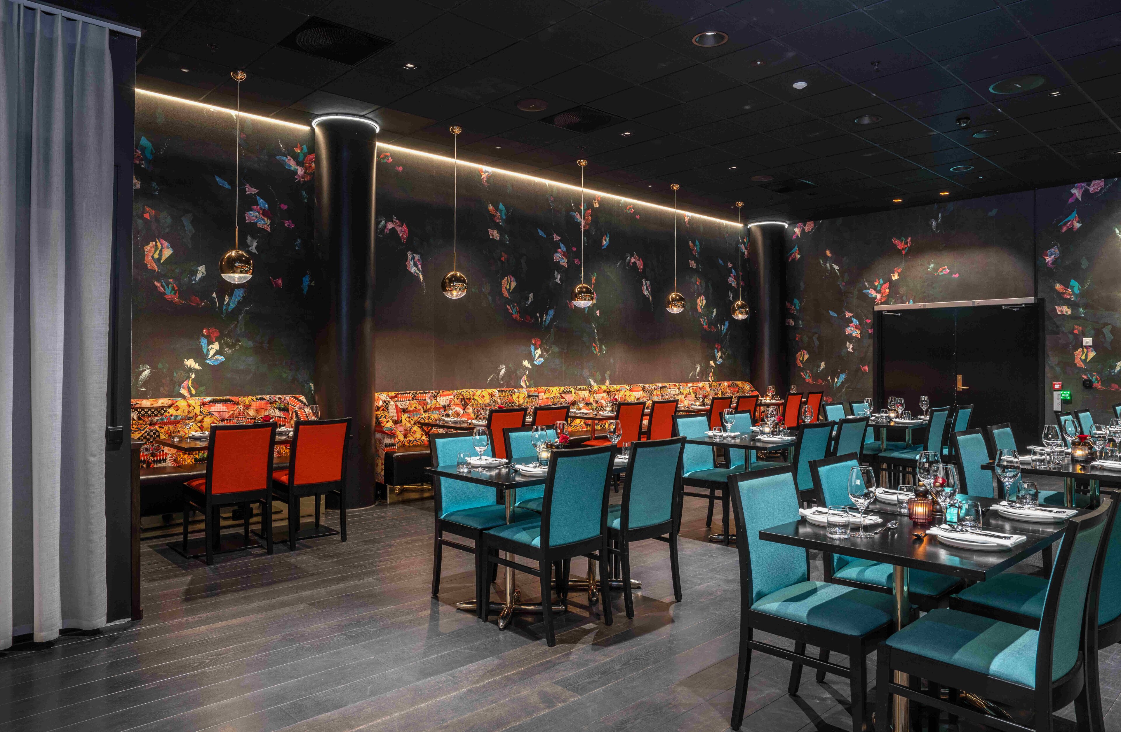 Um restaurante com uma mesa comunitária grande e cabines individuais, cada uma com um abajur.