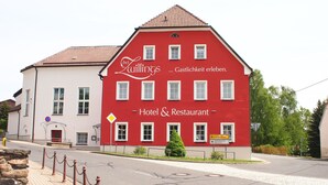 Um edifício vermelho com janelas brancas, identificado como hotel e restaurante.