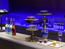 Uma área de bar com diversos frascos e copos, incluindo um suporte escalonado com vários copos.