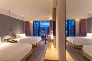Quarto de hotel com duas camas, uma escrivaninha e vista para área externa.