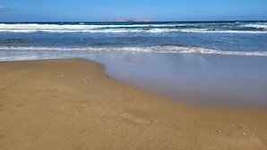 Uma praia com céu claro e ondas.