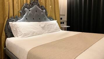 Cama bem arrumada com cabeceira estofada, roupa de cama branca e manta bege.