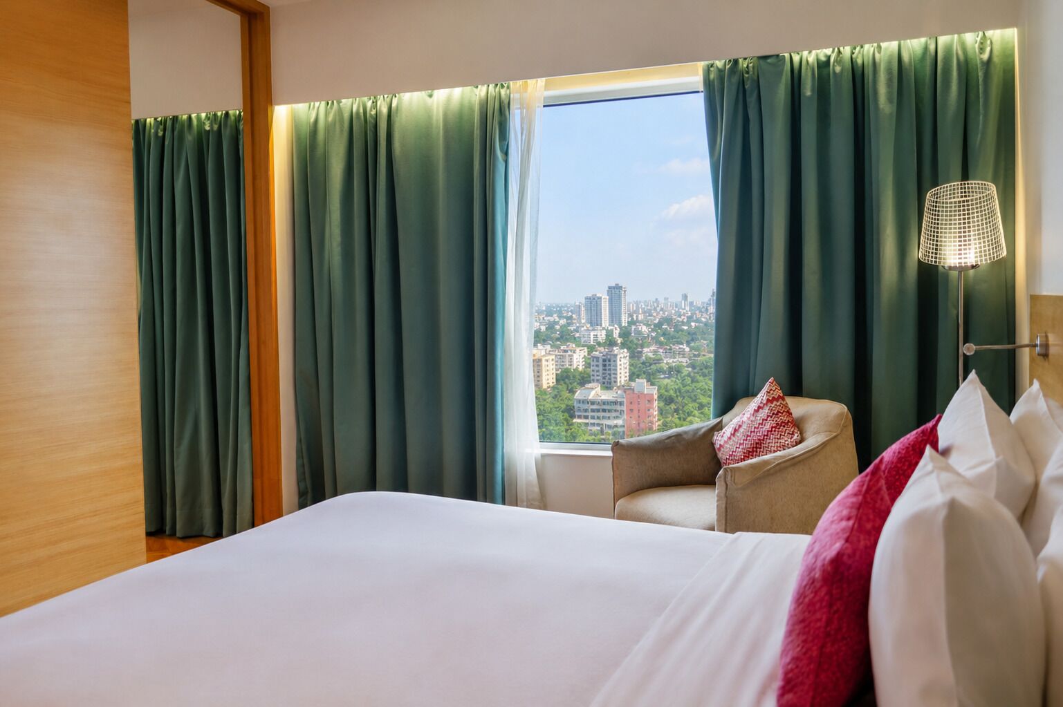 Quarto de hotel com cama, cadeira, vista da cidade e abajur.