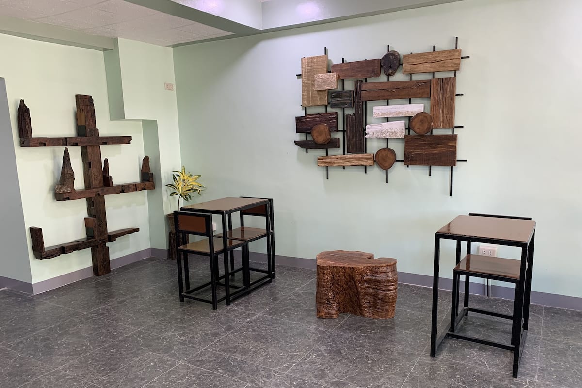 Um quarto com piso de mármore, uma mesa de madeira, um banquinho de madeira e uma prateleira de madeira fixada na parede.