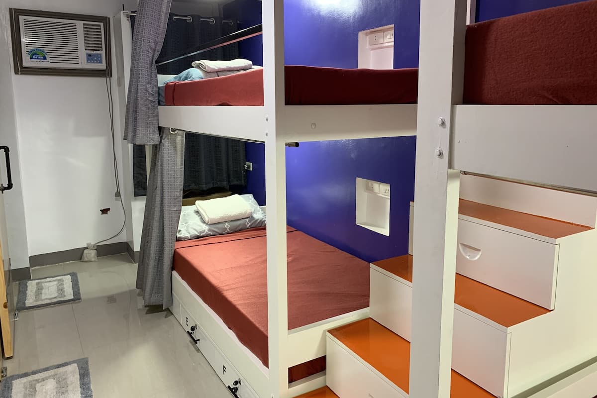 Quarto com beliche, janela, aquecedor e uma pequena prateleira.