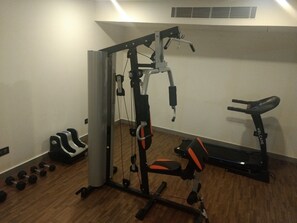Uma academia com esteira ergométrica, aparelhos de musculação e halteres.