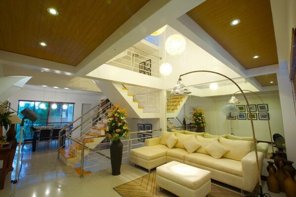 Uma sala de estar ampla com escada, sofá e área de jantar.