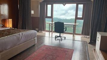 Quarto com uma cama grande, uma escrivaninha e vista para o exterior.