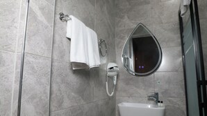 Casa de banho com uma pia branca, um secador de cabelo, um porta-toalhas e um espelho.
