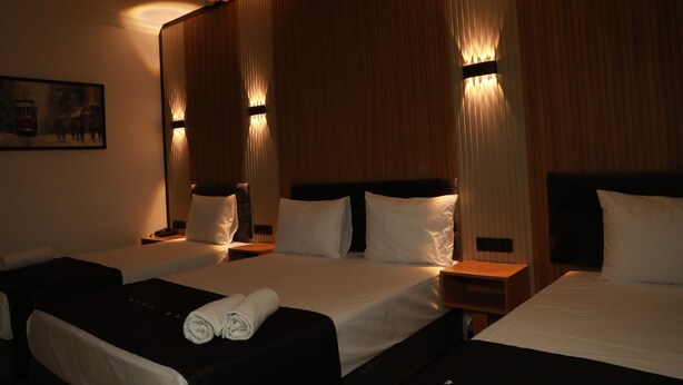 Quarto de hotel com duas camas, cabeceiras de madeira e iluminação embutida na parede.