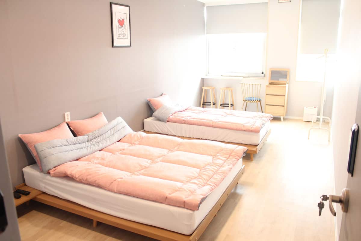 Quarto com duas camas, uma escrivaninha e uma cadeira.
