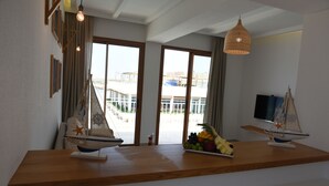 Quarto moderno com balcão de madeira, dois barquinhos de modelo, uma cesta de frutas e uma televisão na parede.