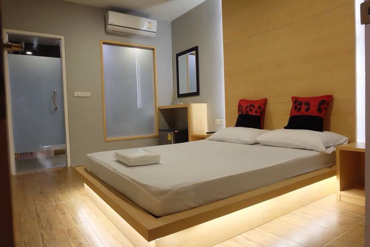 Quarto moderno com cama, mesas de cabeceira, guarda-roupa e espelho.