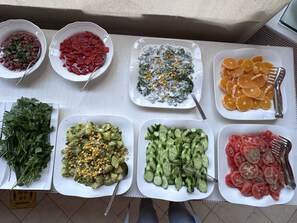 Uma mesa com diversos pratos, incluindo saladas, legumes e frutas.