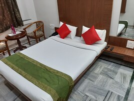 Uma cama bem arrumada com almofadas brancas e vermelhas, um cobertor verde e uma cabeceira de madeira.
