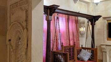 Quarto tradicional com cama de dossel, mobiliário de madeira ornamentado e detalhes esculpidos nas paredes.