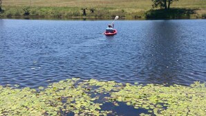 Um lago calmo com uma pessoa praticando caiaque.