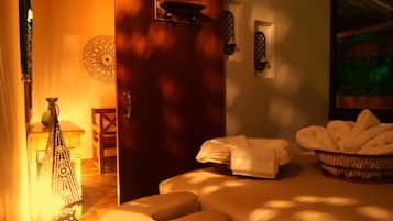 Um quarto aconchegante com porta de madeira, uma mesinha com abajur, um banco estofado e uma cesta de toalhas.